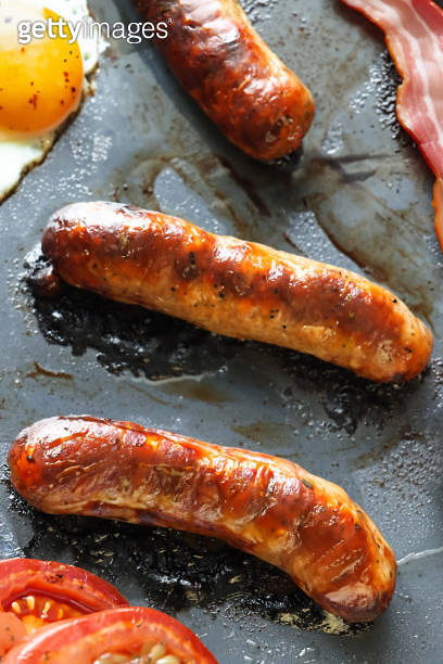 Close-up image of row of grilled pork sausages, bacon rasher, sunny ...