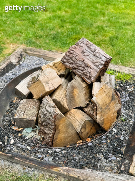 Close-up image of fire pit (buried metal fire bowl) piled with split ...