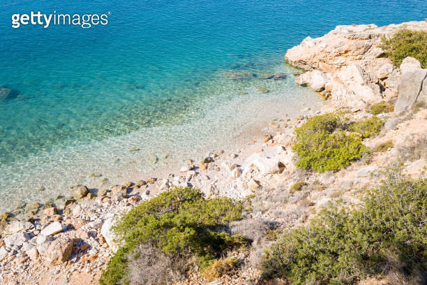 The arid rocky coast and its green countryside along small beaches, in ...