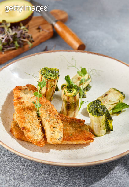 Close-up vertical side view of tempura perch fillet with zucchini rolls ...