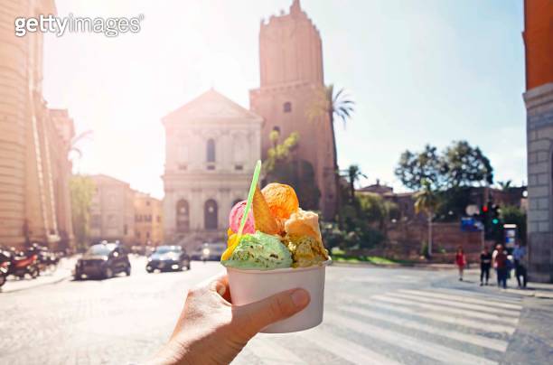 Italian bright sweet ice cream gelato cone with different flavors held ...