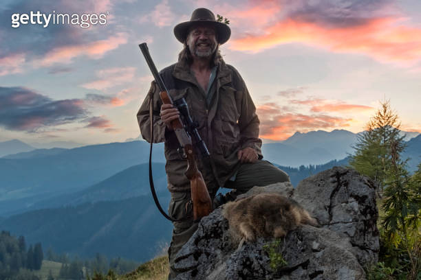 Hunter in the Alps in front of the hunted Marmot (1999751692) - 게티이미지뱅크