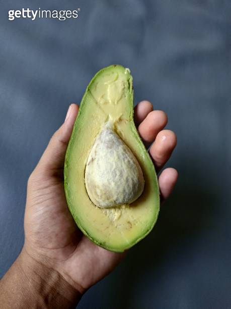 hand holding a split avocado with the seed still attached split avocado ...
