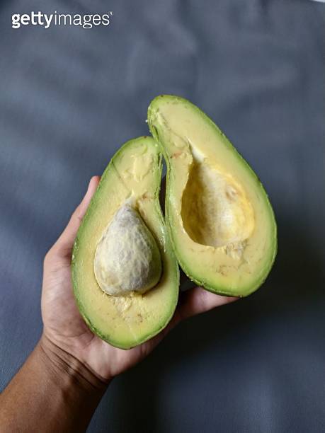 hand holding a split avocado with the seed still attached split avocado ...