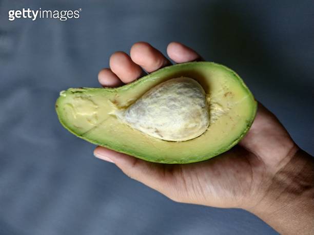 hand holding a split avocado with the seed still attached split avocado ...