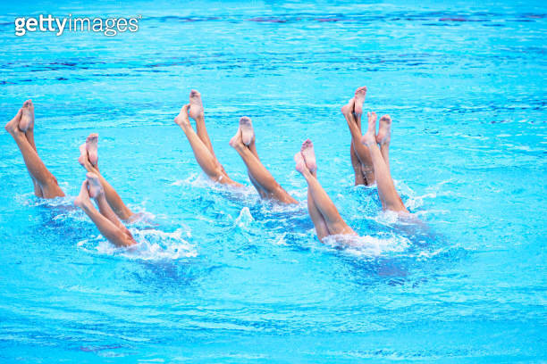 Artistic swimming team in swimming pool performing synchronized legs ...