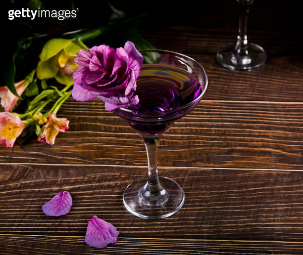 Cold purple violet exotic cocktail in glass with decorated flowers and ...