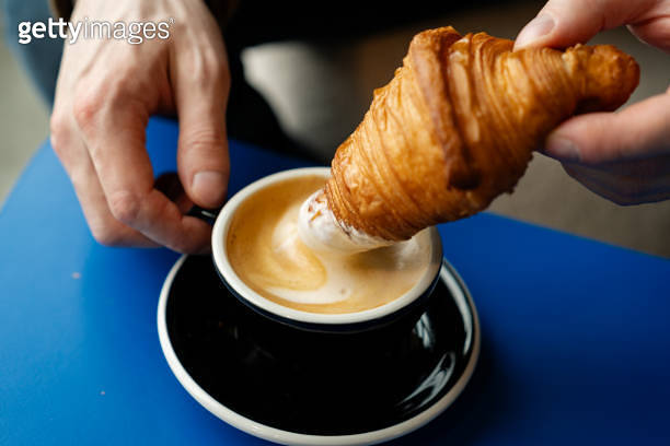 Dipping croissant in a coffee. Delicious morning breakfast with fresh ...