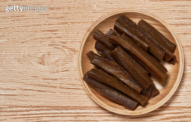 flat lay top view pile of black pickle burdock root in wooden bowl on ...