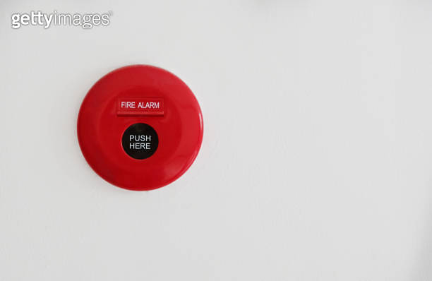 Alarm switch on a wall with a fire alarm symbol, representing a safety ...