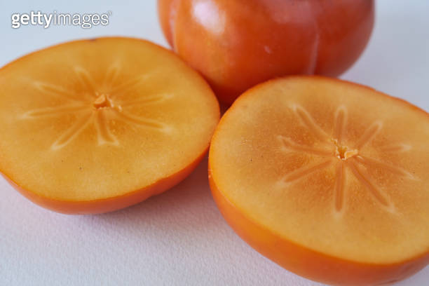 Fresh ripe persimmon fruits on a light background. Seedless persimmons ...