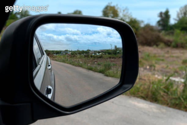Inside view of mirrors wing. Rear view of a gray car with asphalt road ...