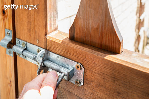 Homeowner seen unlocking a wooden gated side entrance by sliding the ...