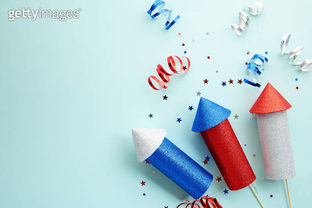 Firework rockets with party streamers on light blue background. Happy ...