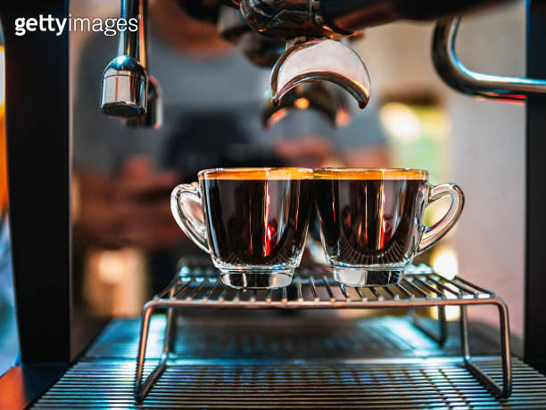 Close up of Espresso shot with coffee crema and Professional coffee machine while preparing two ...