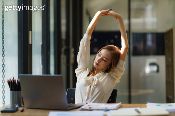 Asian businesswoman working in an office stretches to relax from work ...