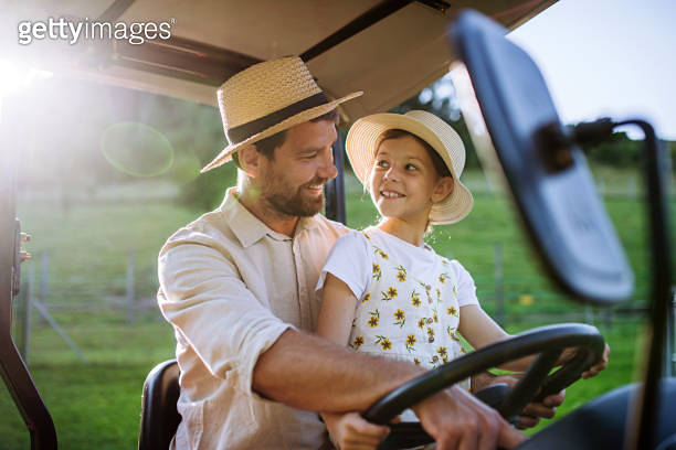 Farmer father riding tractor with his daughter. Girl growing up on ...