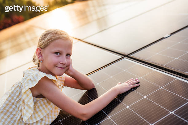 Girl lying on roof with solar panels during sunset, smiling. Rooftop ...