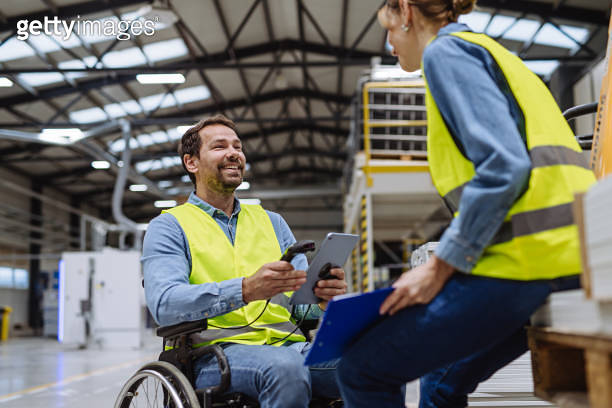 Portrait of man in wheelchair working in modern industrial factory ...