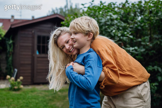 Mother hugging son from behind, bonding moment. Real family, real ...
