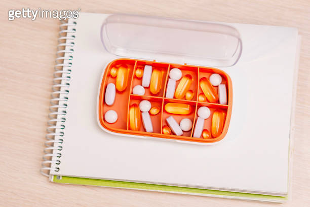 Orange-colored vitamins and medications are in the pill box for a week ...