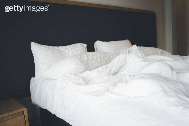 Messy untidy bed with white pillow and blanket after sleep in bedroom ...