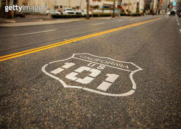 Highway 101 sign painted on the black asphalt road with city diffused ...