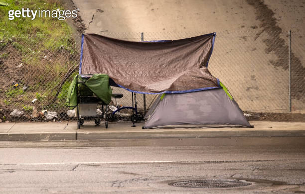 A homeless camp with a black tarp under a bridge during a rain storm ...