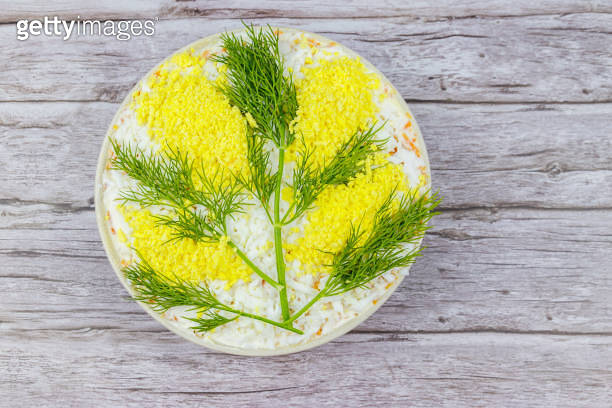 Traditional russian layered salad Mimosa decorated with sprigs of ...