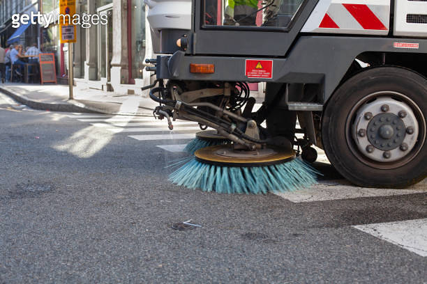cleaning city street, closeup of brush of a street sweeper vehicle ...