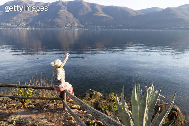 Woman contemplating nature by the lake, arms wide open, embracing life ...