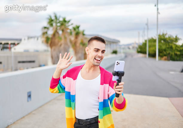 Gay male vlogger recording content for social media with a mobile phone ...