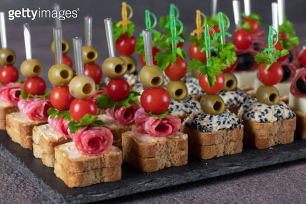 Assortment of canapes with cherry tomatoes, sausage, cheese, olives and ...