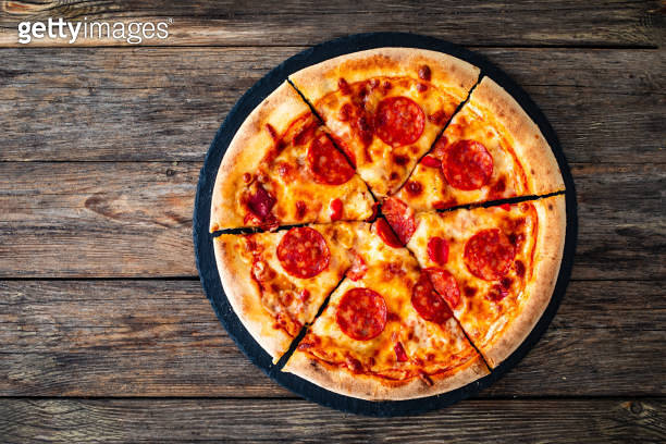 Circle pizza chorizo with mozzarella served on stony black plate on ...