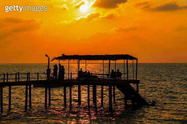 Tourists relaxing on jetty watching dramatic golden sunset at agatti Island lakshadweep 이미지 ...