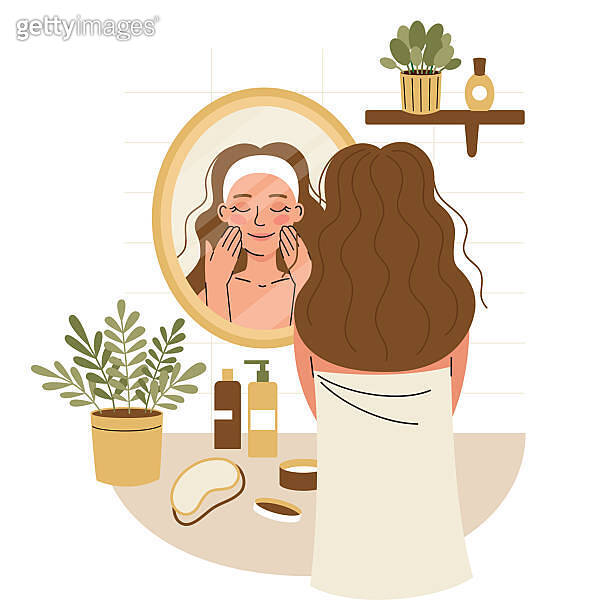 A woman is applying cream to her face in front of the bathroom mirror ...