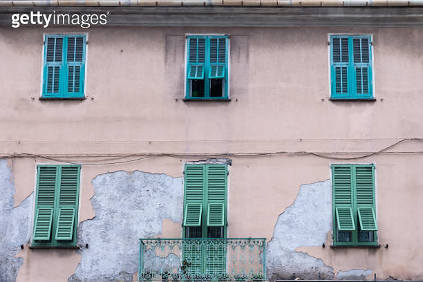 Old three-story building with windows with wooden exterior shutters ...