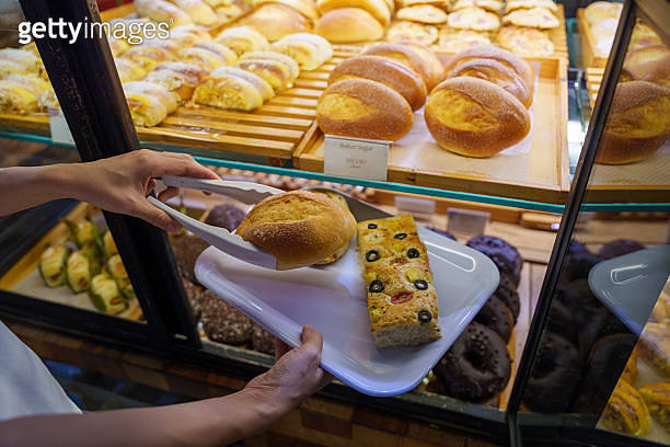 Selecting fresh bread at bakery display with serving tongs (2208924284 ...