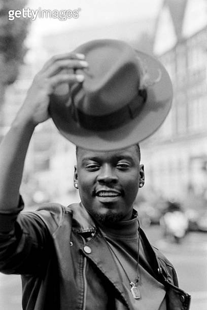 Stylish man lifting his hat in a grainy black and white portrait ...
